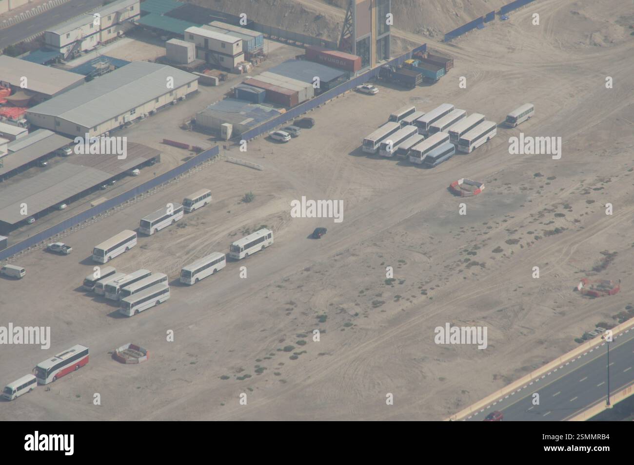 A row of white buses parked in a dusty lot in Dubai. This bus storage ...