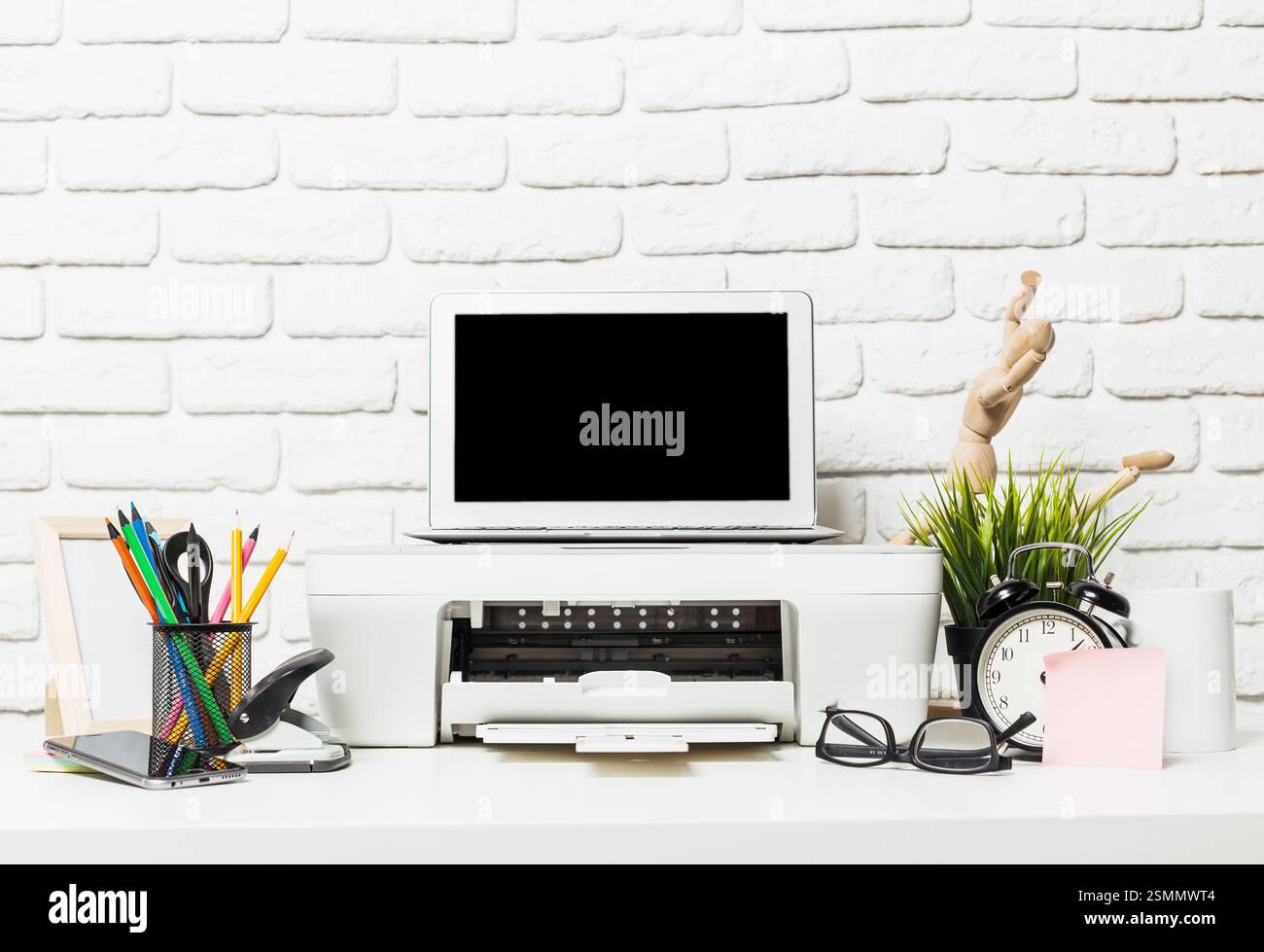 Creative workspace setup with printer, laptop, and various office ...