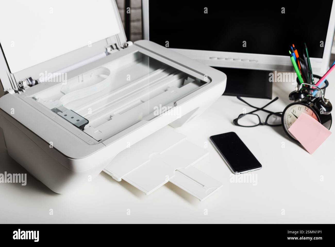 Desk setup with printer, smartphone, and clock during work hours in a ...