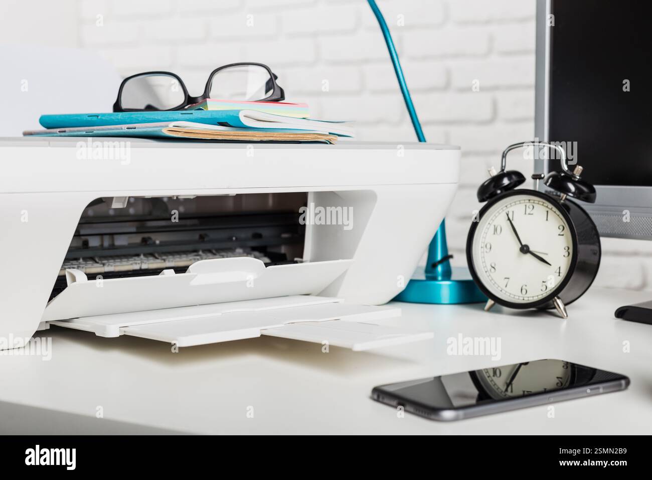 Printer on desk with glasses, clock, notebook, and smartphone at ...