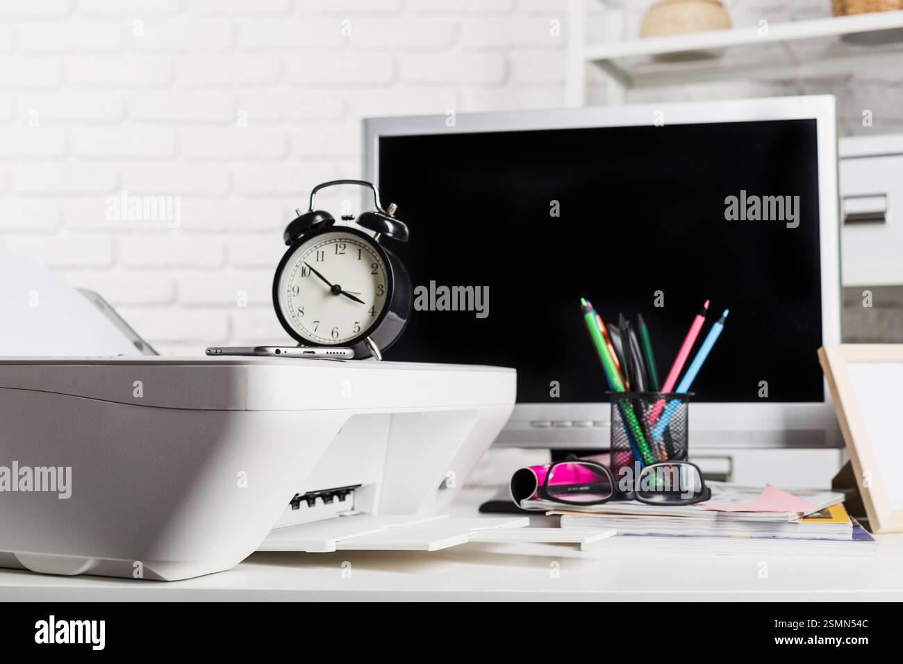 Office workspace with a clock, printer, and computer showcasing a ...
