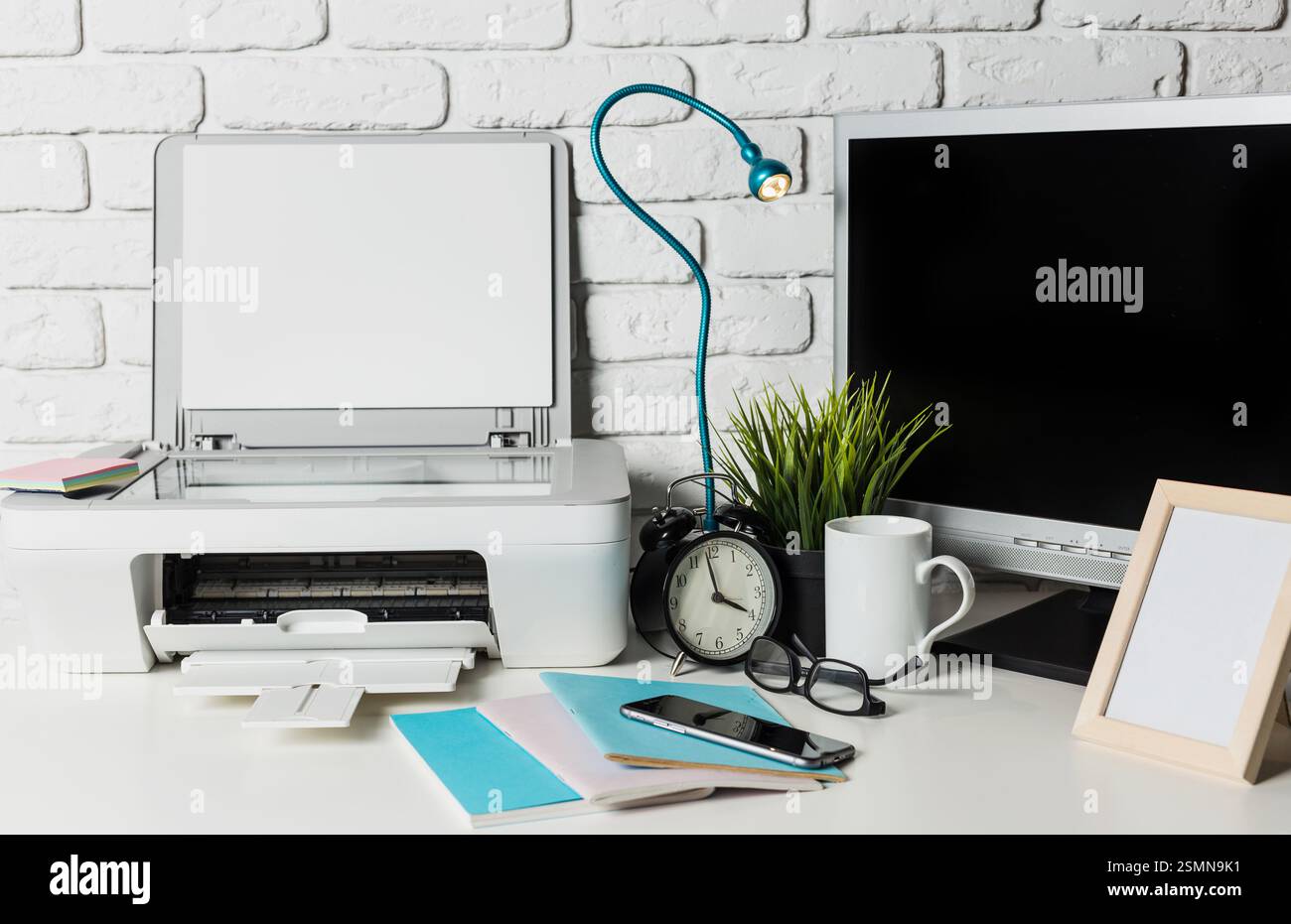 Workspace essentials showcasing printer, monitor, clock, and desk items ...