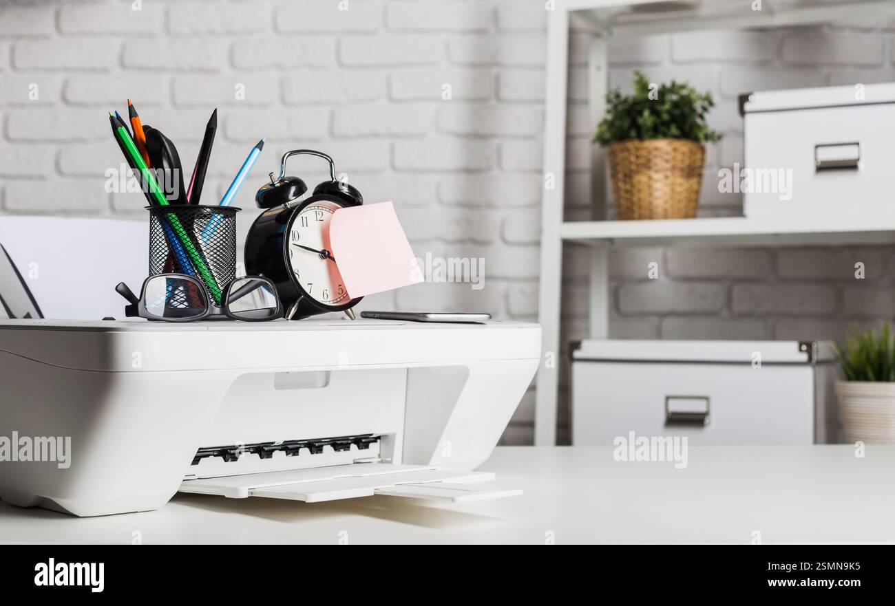 Office workspace with printer, clock, and stationery on a modern desk ...