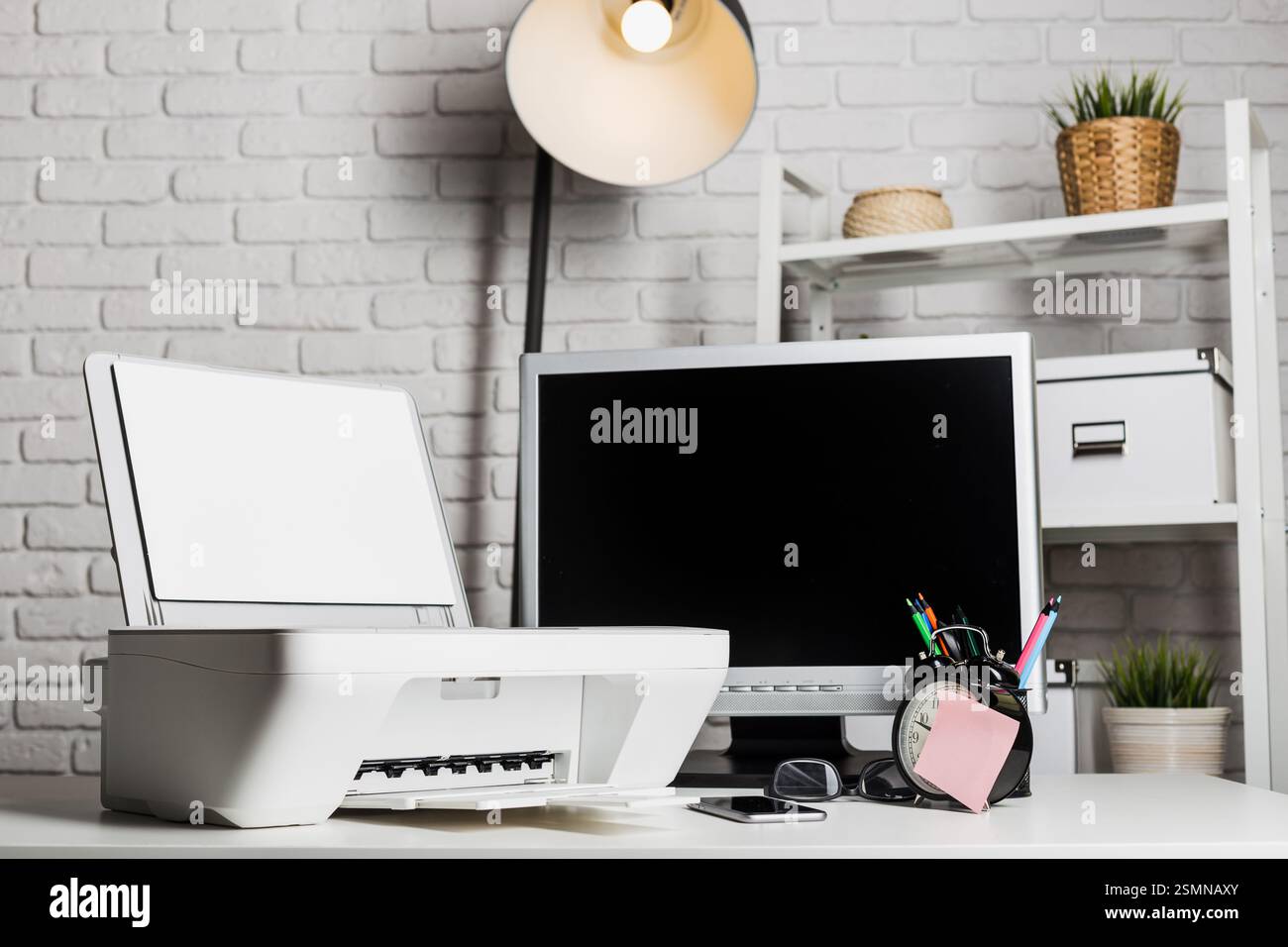 Workspace featuring computer, printer, clock, and stationery in a ...