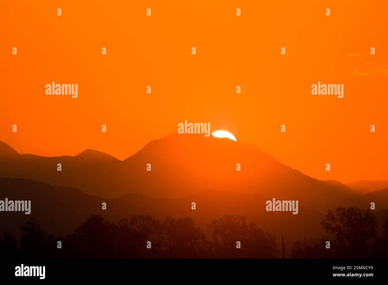 Dawn - the sun disk slowly rolls from behind the mountain, illuminating ...