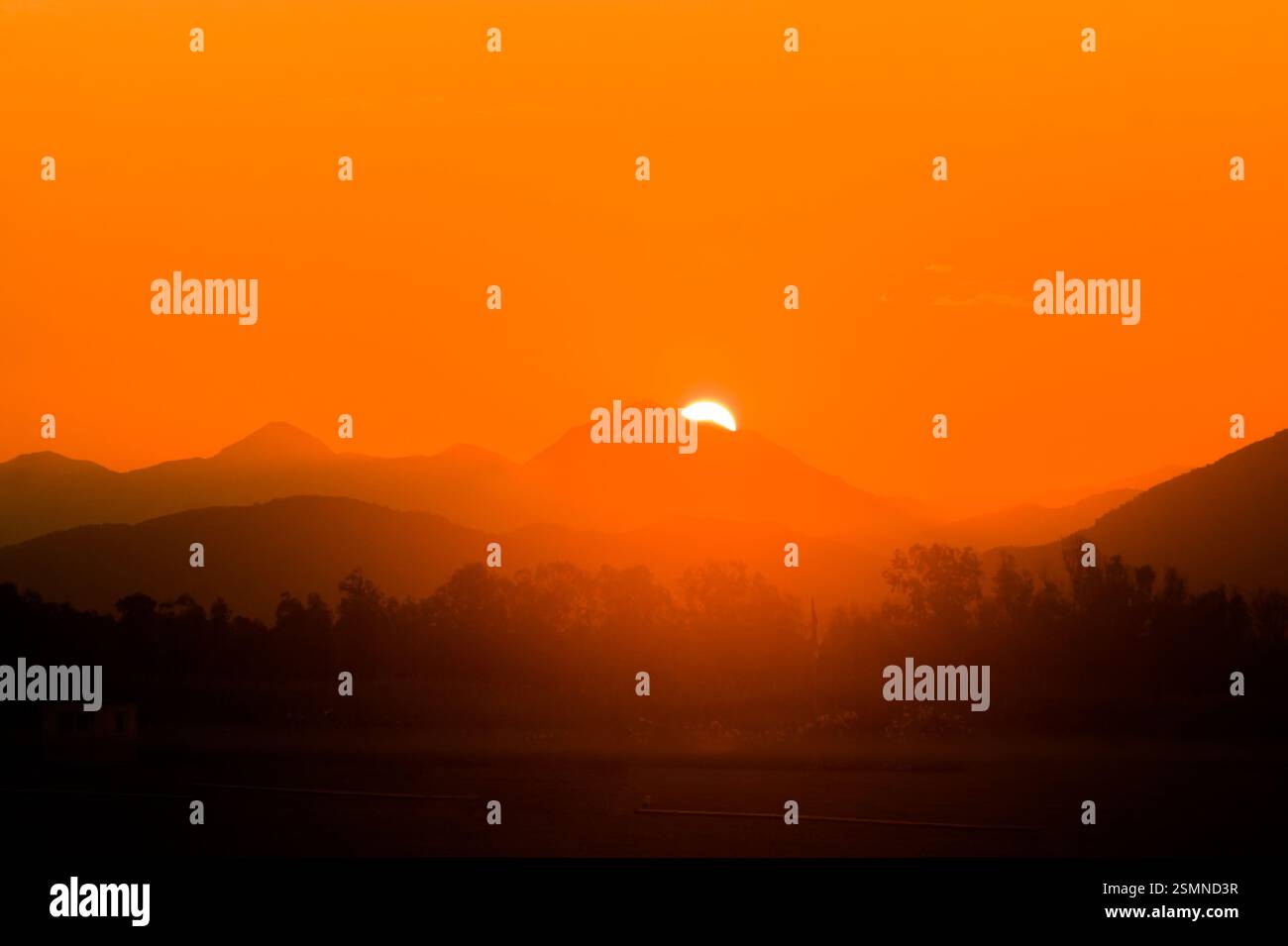 Dawn - the sun disk slowly rolls from behind the mountain, illuminating ...