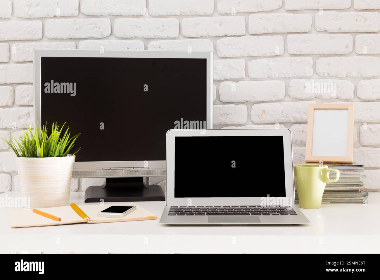 Modern workspace featuring a laptop, desktop monitor, and decorative ...