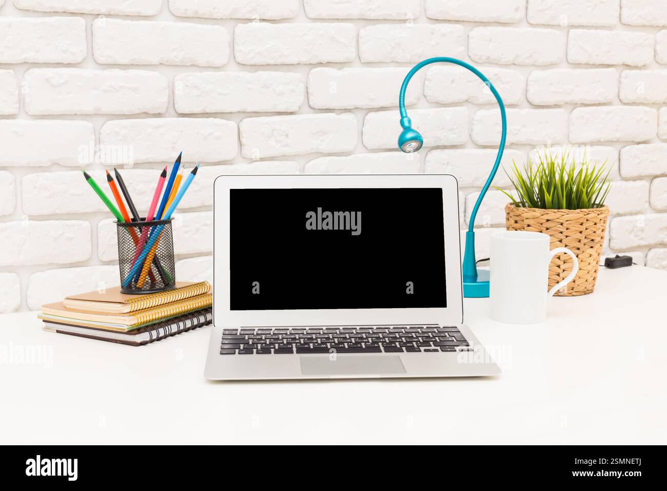 Workspace with laptop, stationery, and desk lamp located in a bright ...