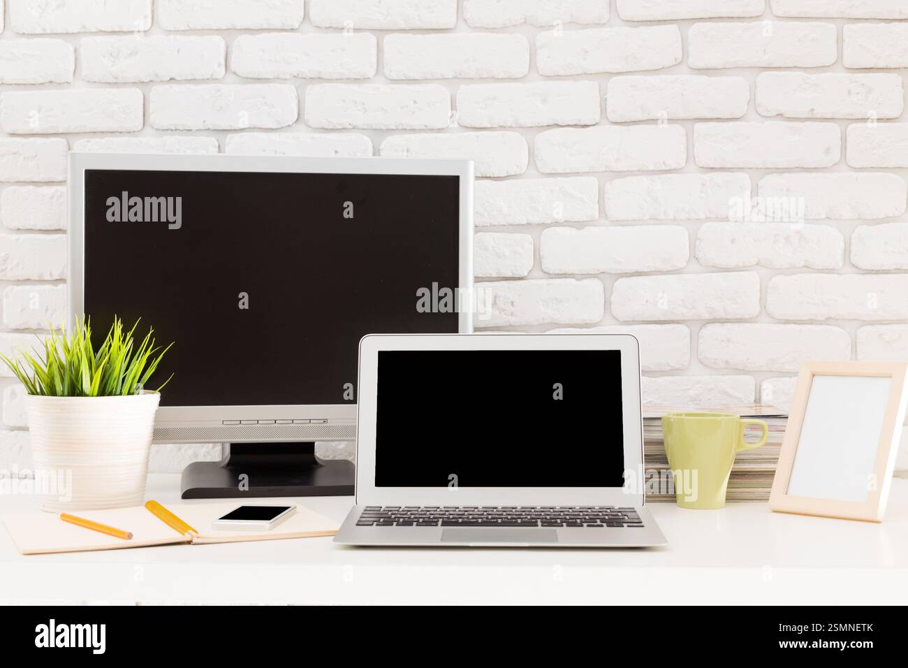 Modern workspace featuring laptops, plants, and stationery set against ...
