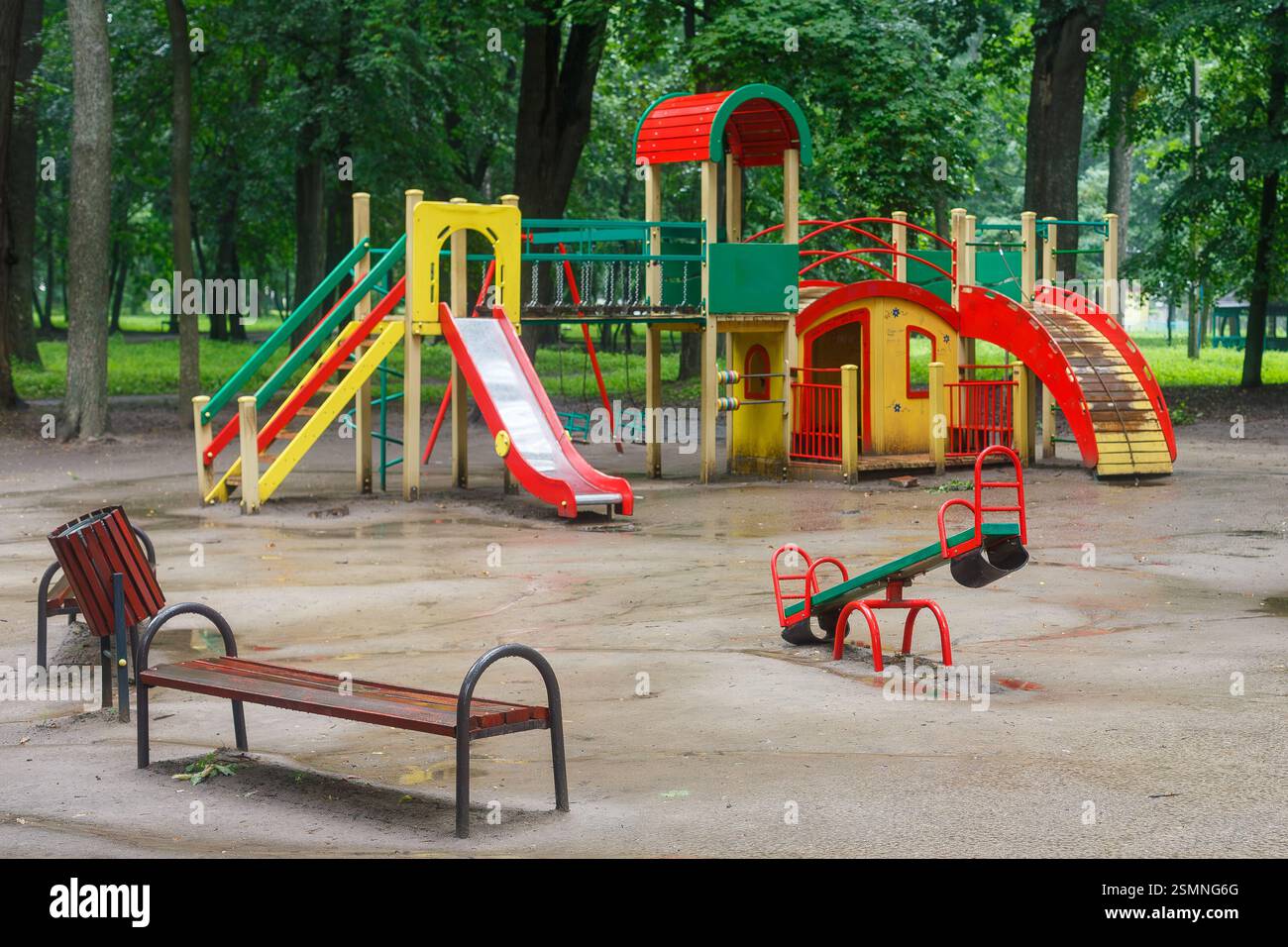 A vibrant playground with slides, swings, and seesaws stands empty on a ...