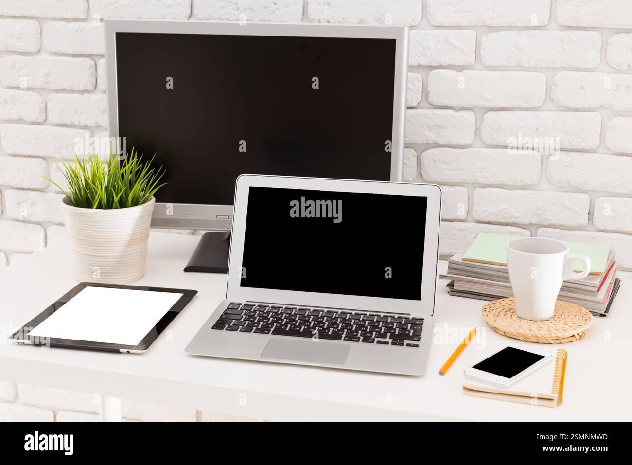 Modern workspace setup featuring laptop, tablet, and decorative plants ...