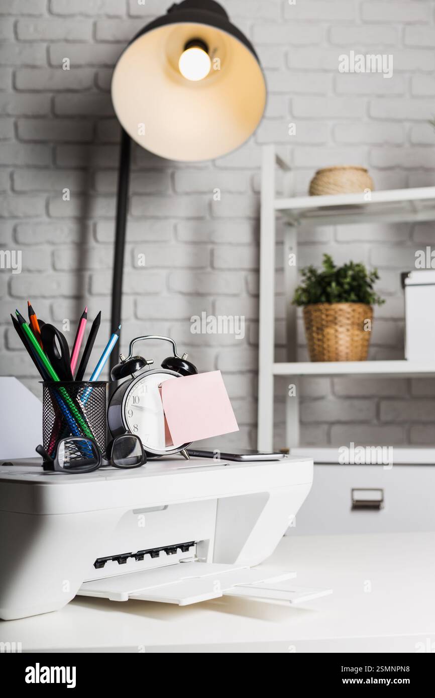 Desk setup with printer, stationery, and clock in a modern workspace ...