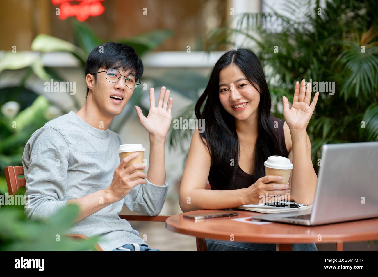 Two cheerful and positive Asian male and female friends are sitting at ...