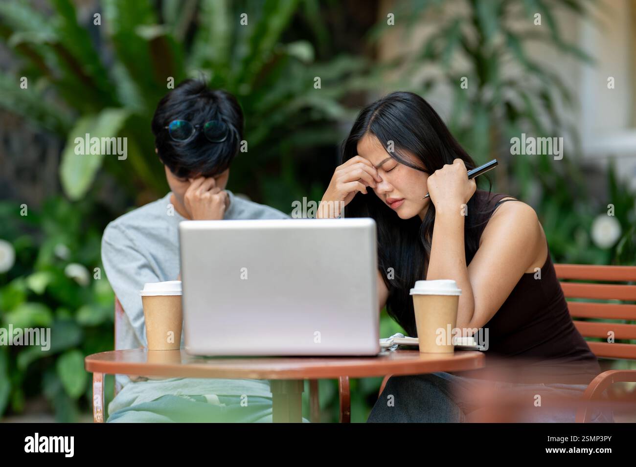 Two stressed and frustrated Asian people are sitting in front of a ...
