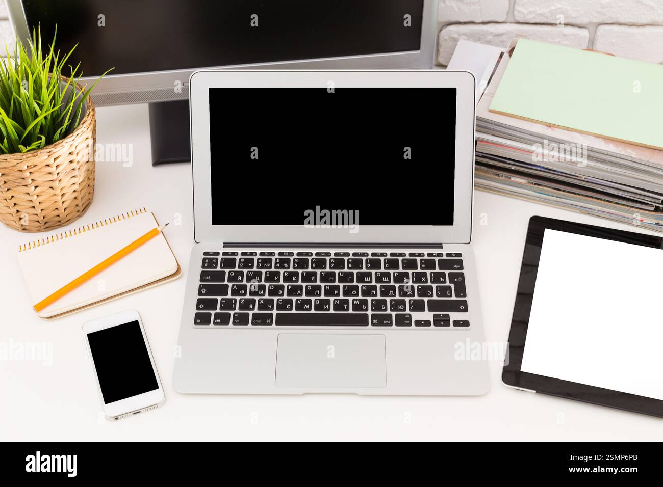 Workspace setup featuring a laptop, smartphone, tablet, and stationery ...