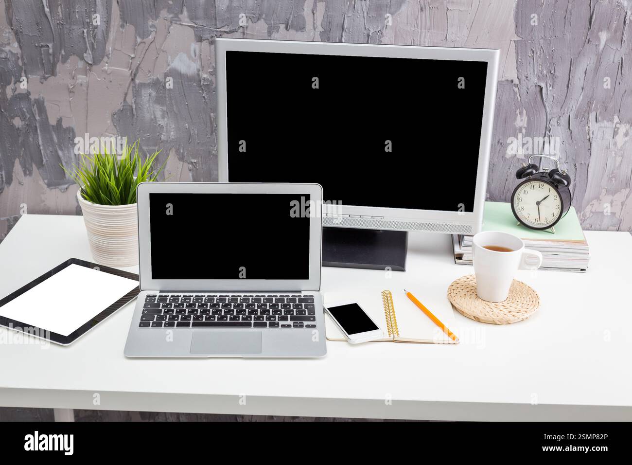 Home office setup with laptop, monitor, and coffee cup on a white desk ...