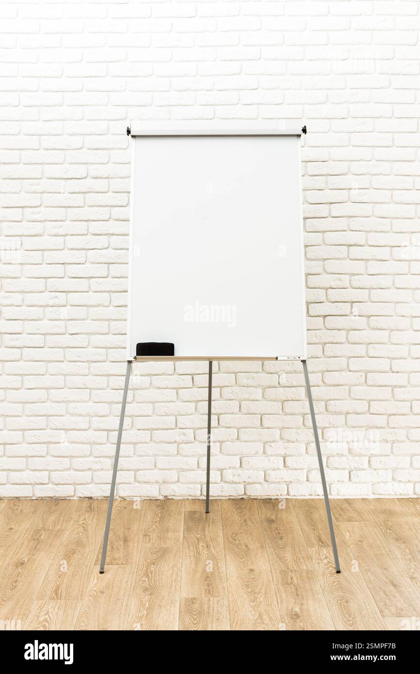 Flip chart set up against a white brick wall in a well-lit indoor space ...
