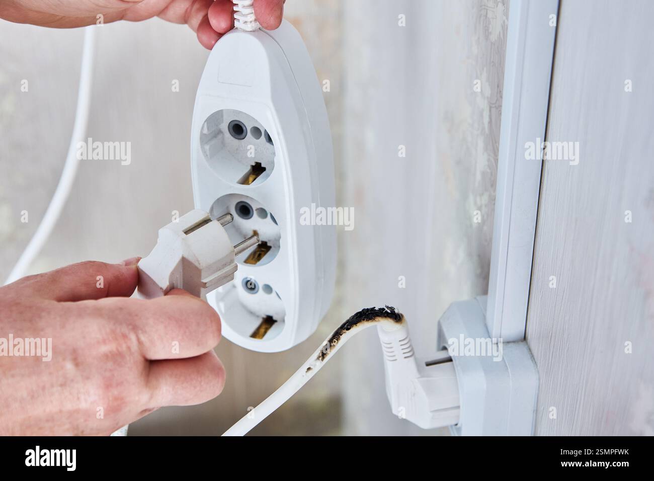 Scorched cable connected to wall outlet and power strip Stock Photo - Alamy