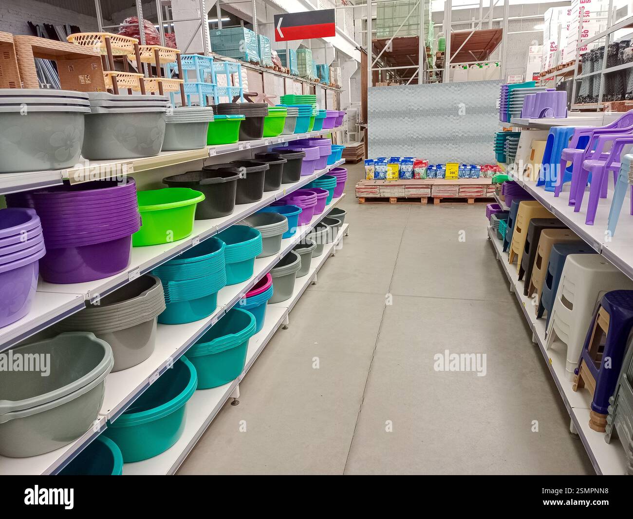 Colorful plastic buckets, basins, and stools neatly arranged on store ...