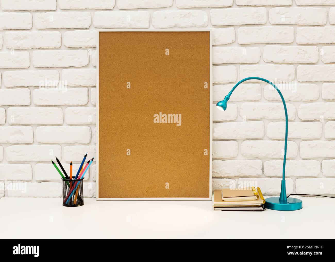 Workspace corner with blank cork board, desk lamp, and stationery items ...