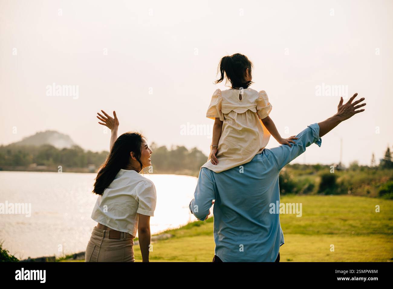 Asian family child girl piggyback riding back on father raising hands ...
