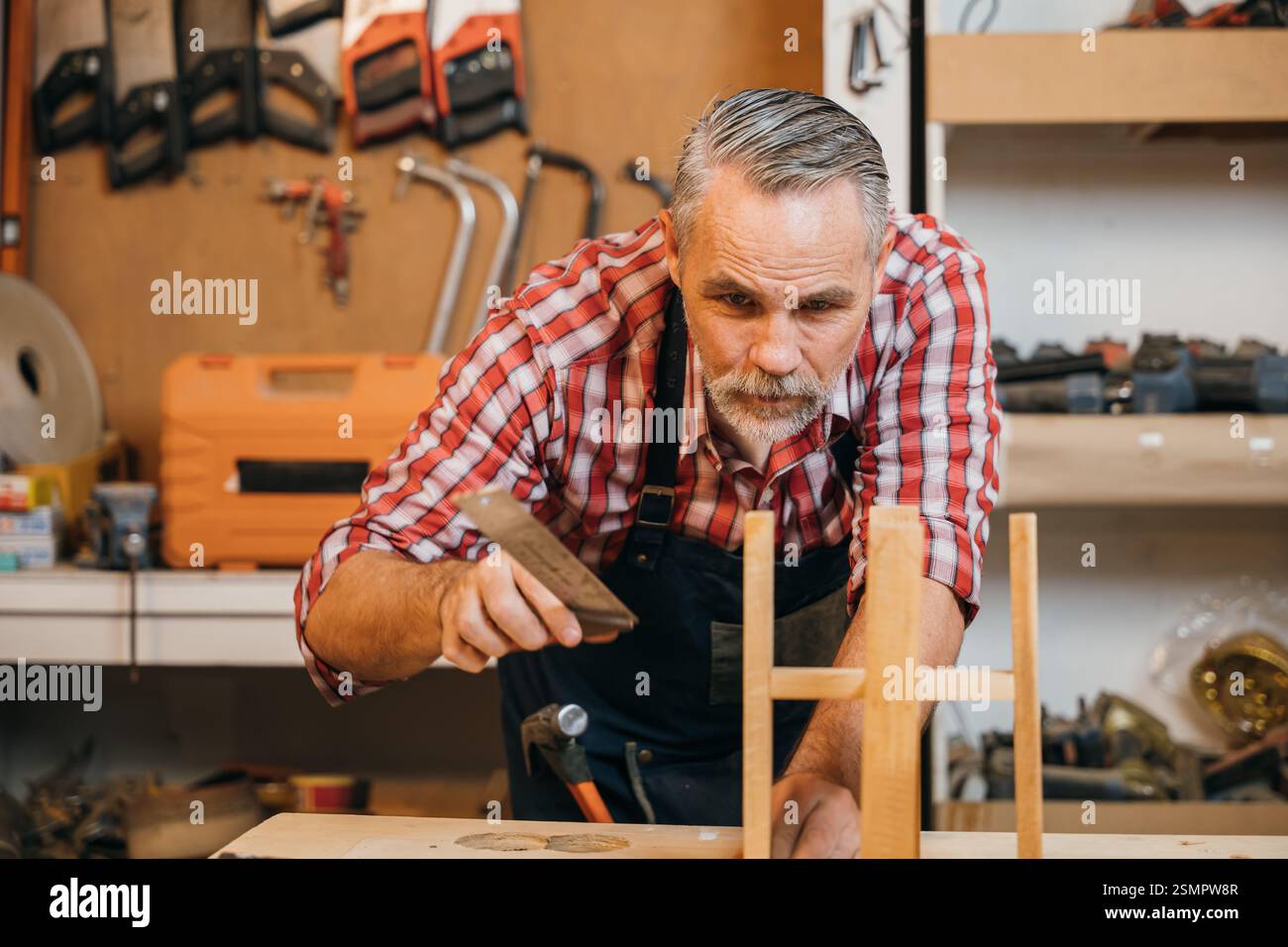 Senior carpenter uses a ruler and set square to measure and assemble a ...