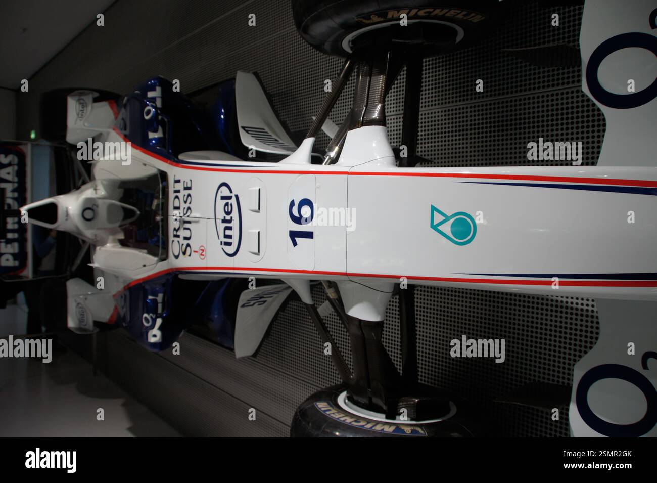 A white racing car with a blue logo and sponsor stickers dominates the ...