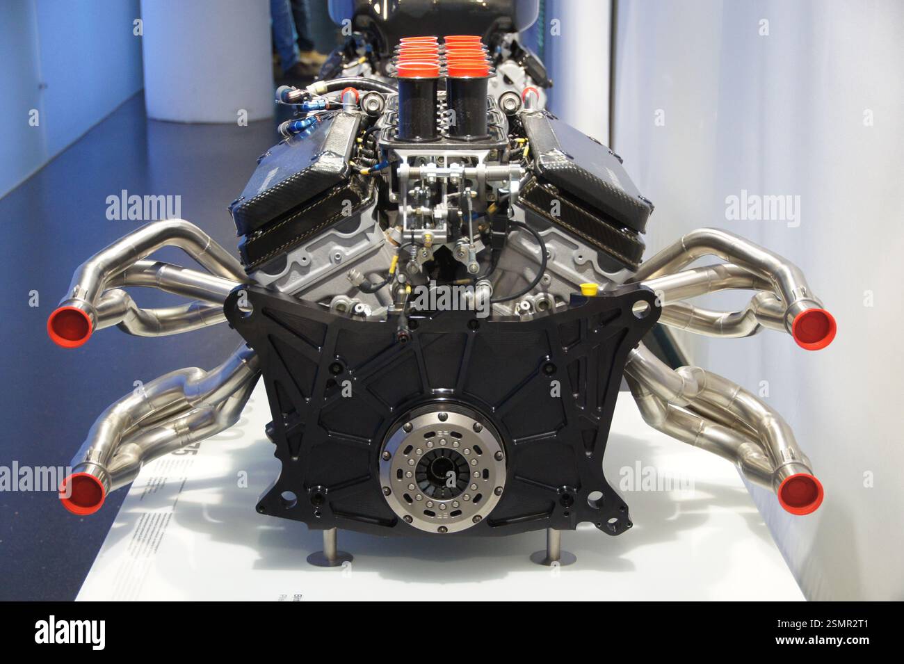 A black model of a V12 engine with multiple exhaust pipes is on display ...