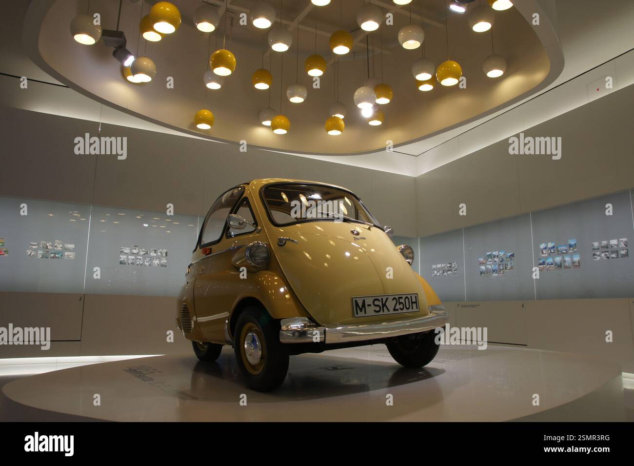 A yellow BMW Isetta microcar sits on a white podium in a brightly lit ...