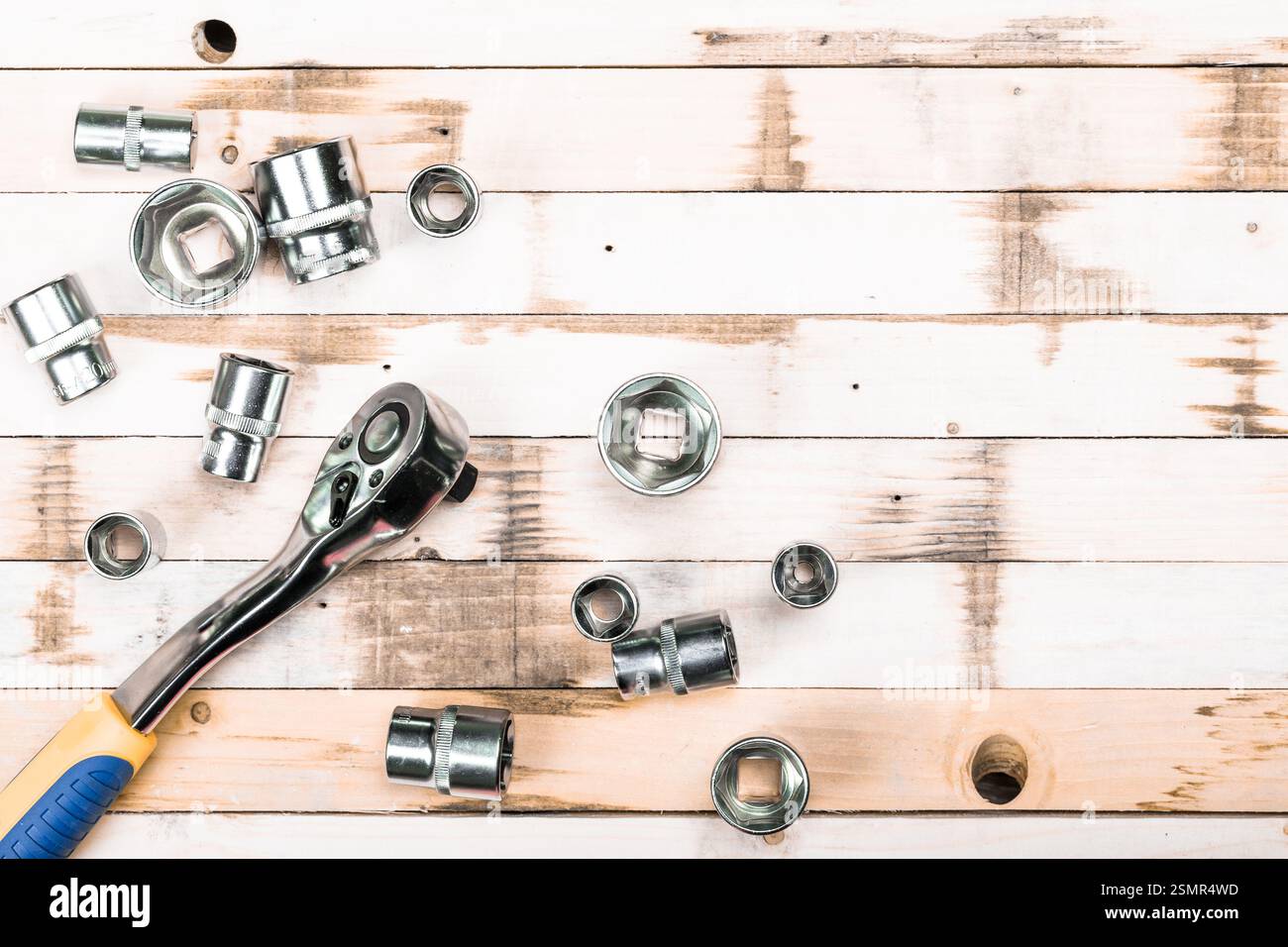 Tools scattered on a wooden workbench with a ratchet wrench and various ...
