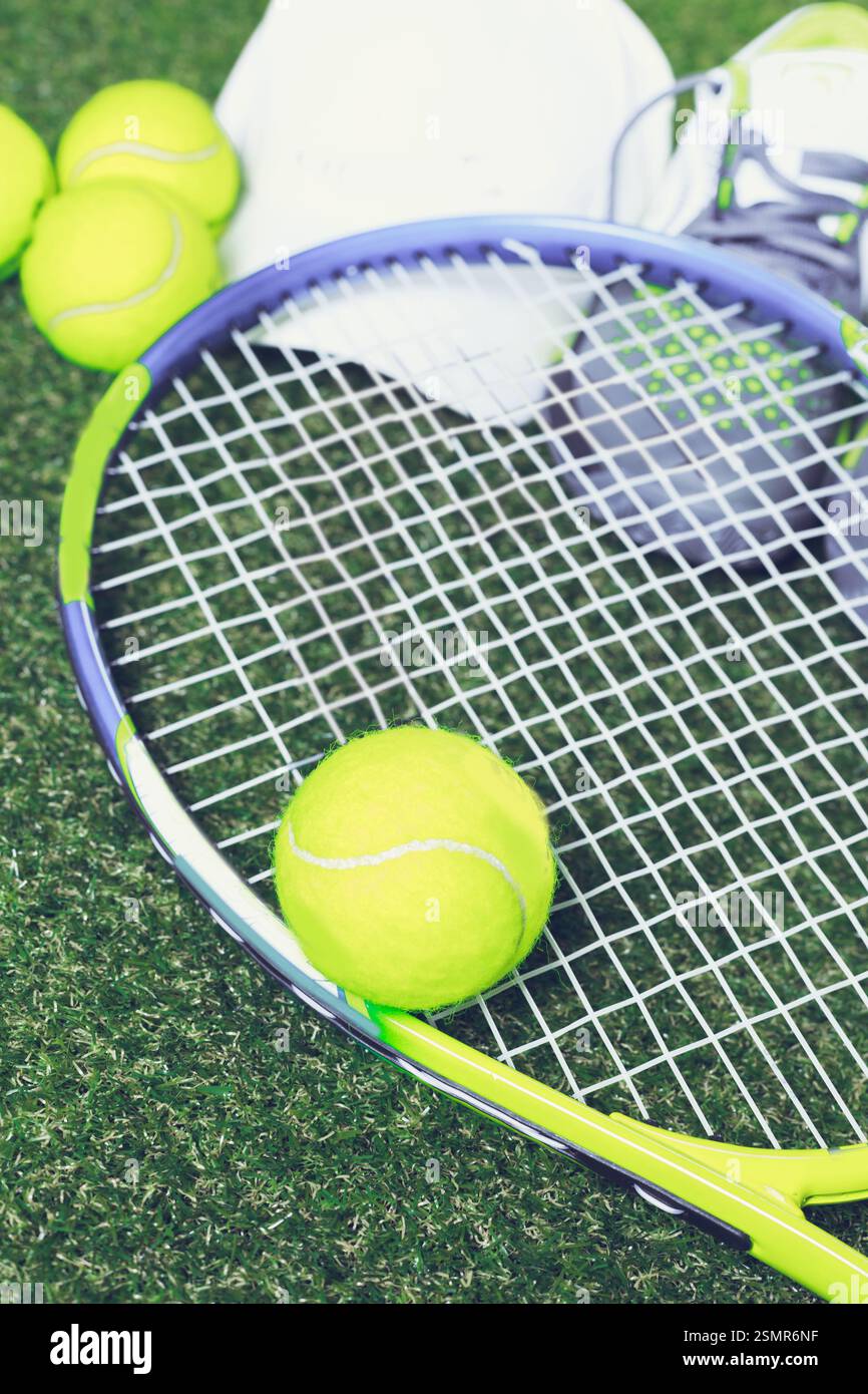 Bright green tennis balls and a racket arranged on synthetic grass for ...
