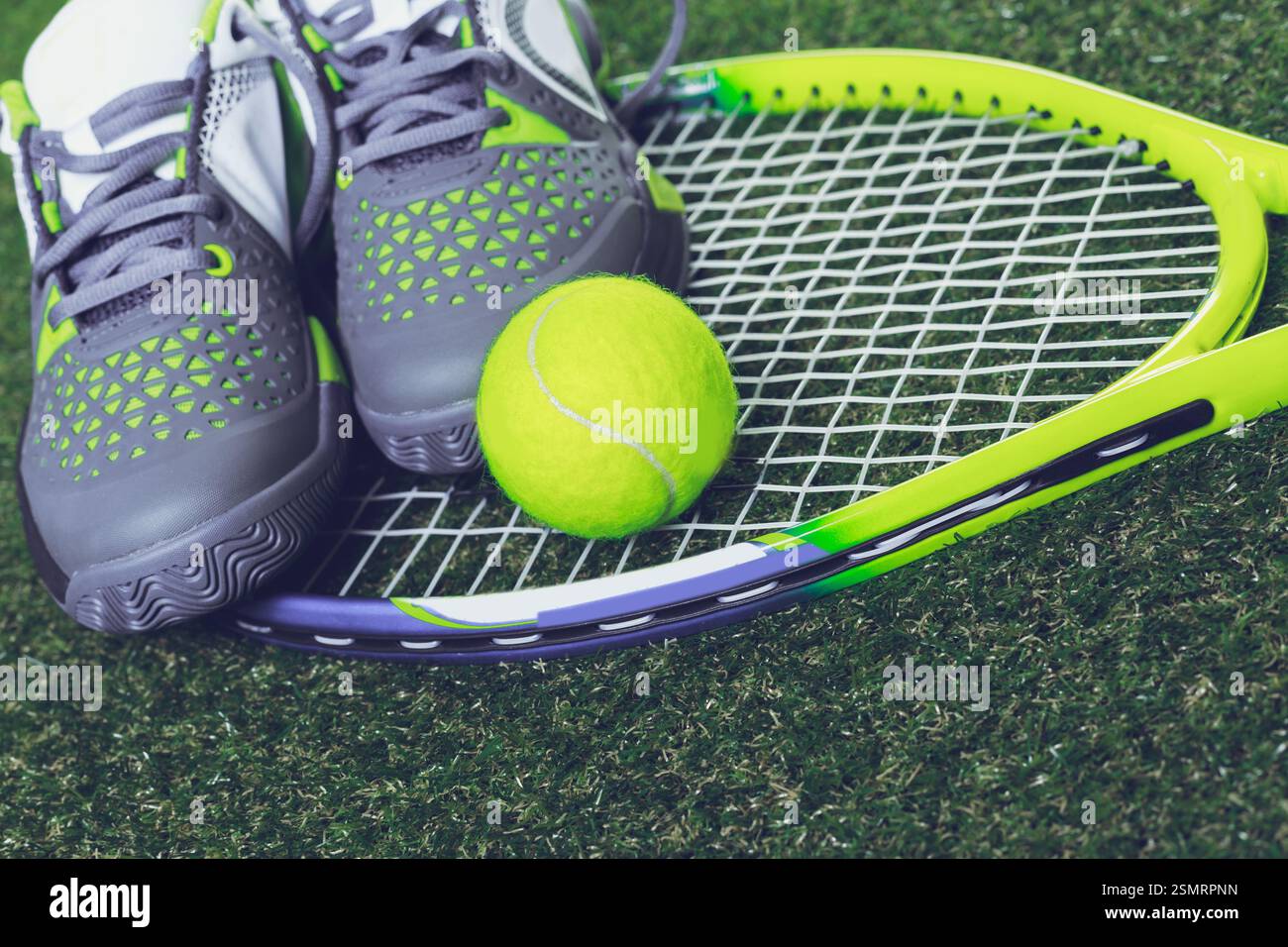 Tennis gear arranged on green court surface with shoes, racket, and ...