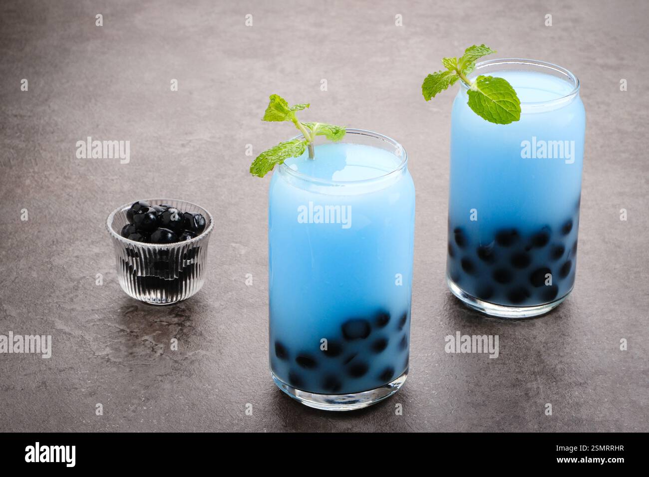 Butterfly pea milk bubble tea with boba tapioca pearls and mint garnish ...