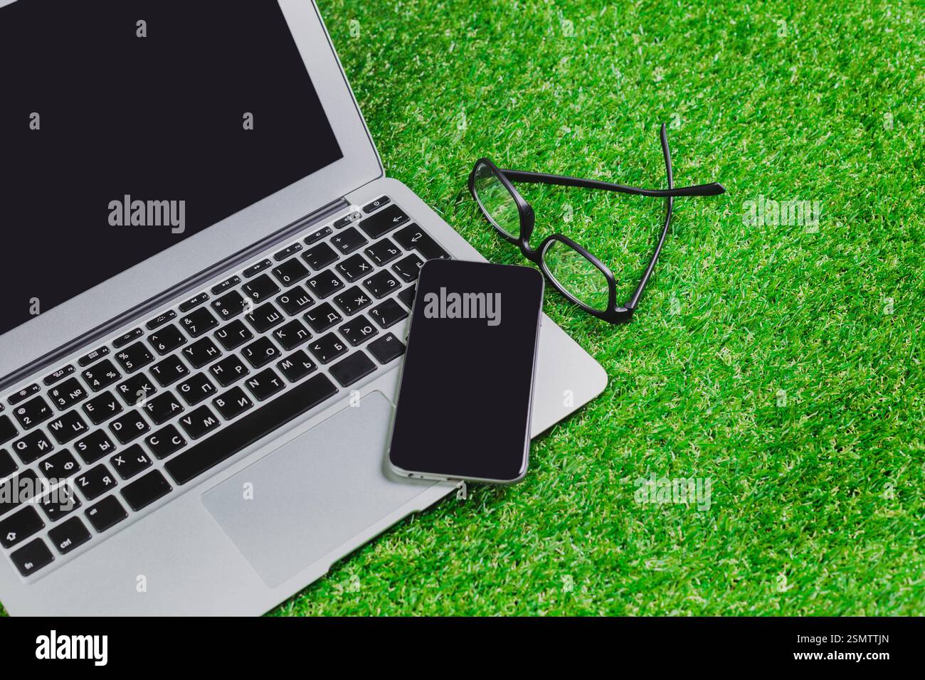 Workstation setup on artificial grass with laptop, smartphone, and ...