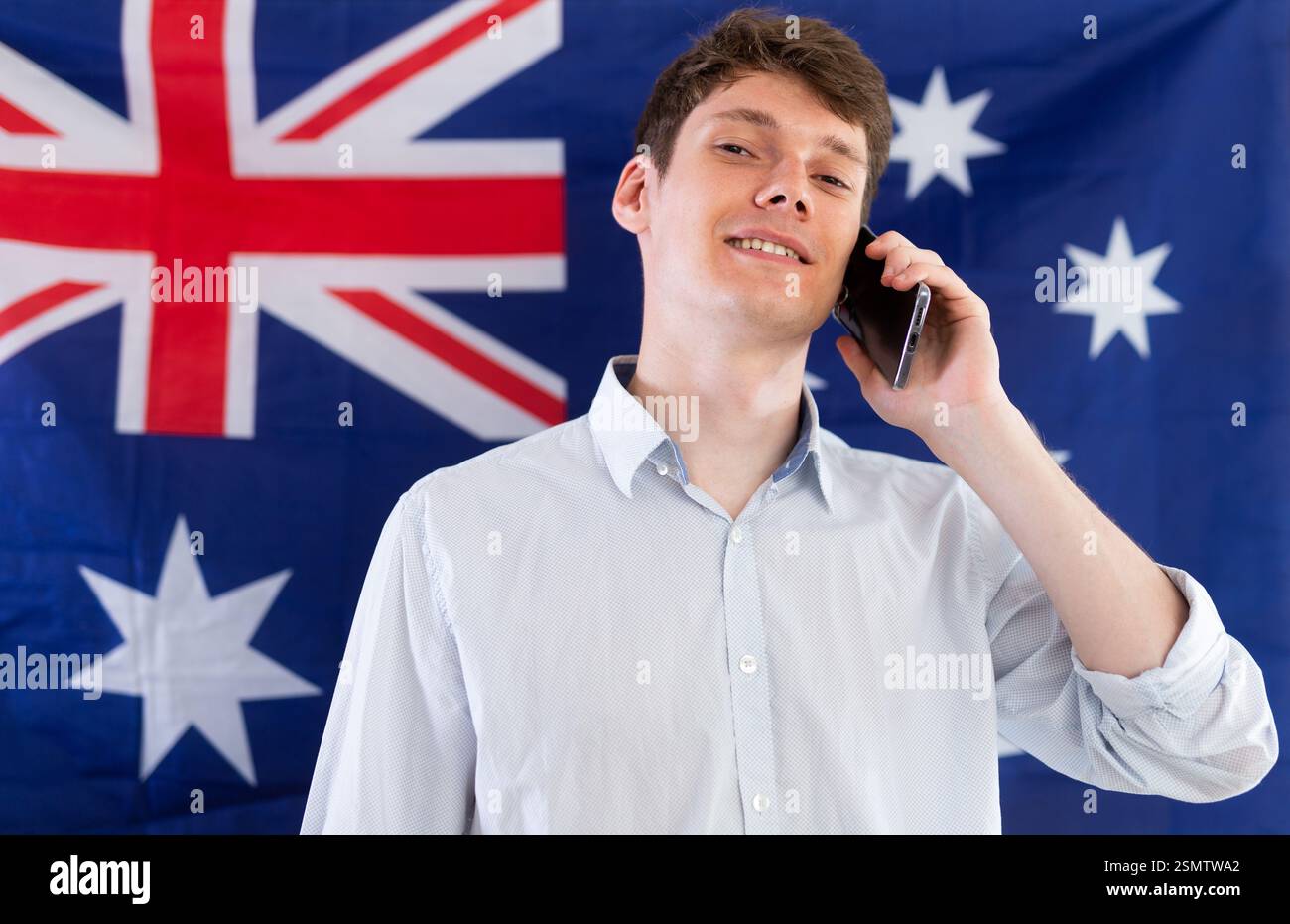 Young guy talking on phone in front of Australian flag Stock Photo - Alamy