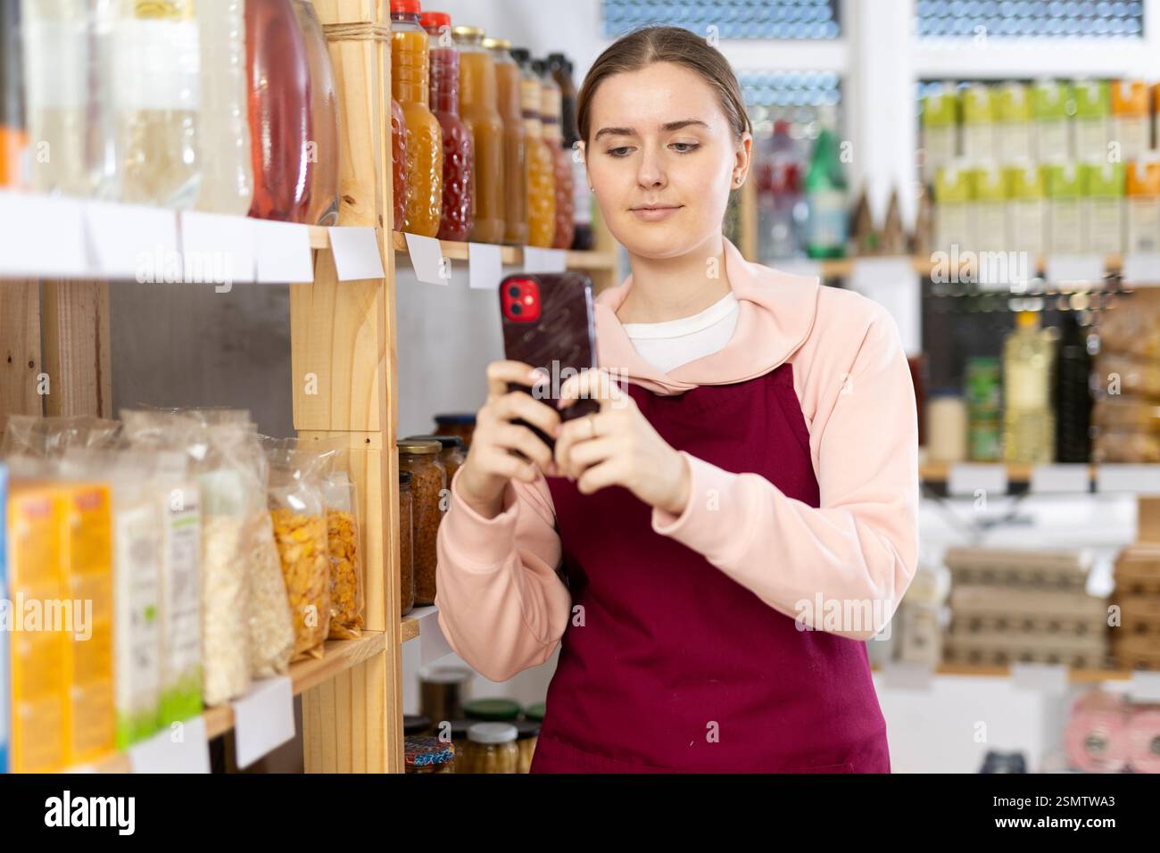 Merchandiser girl takes pictures of goods on supermarket shelves ...