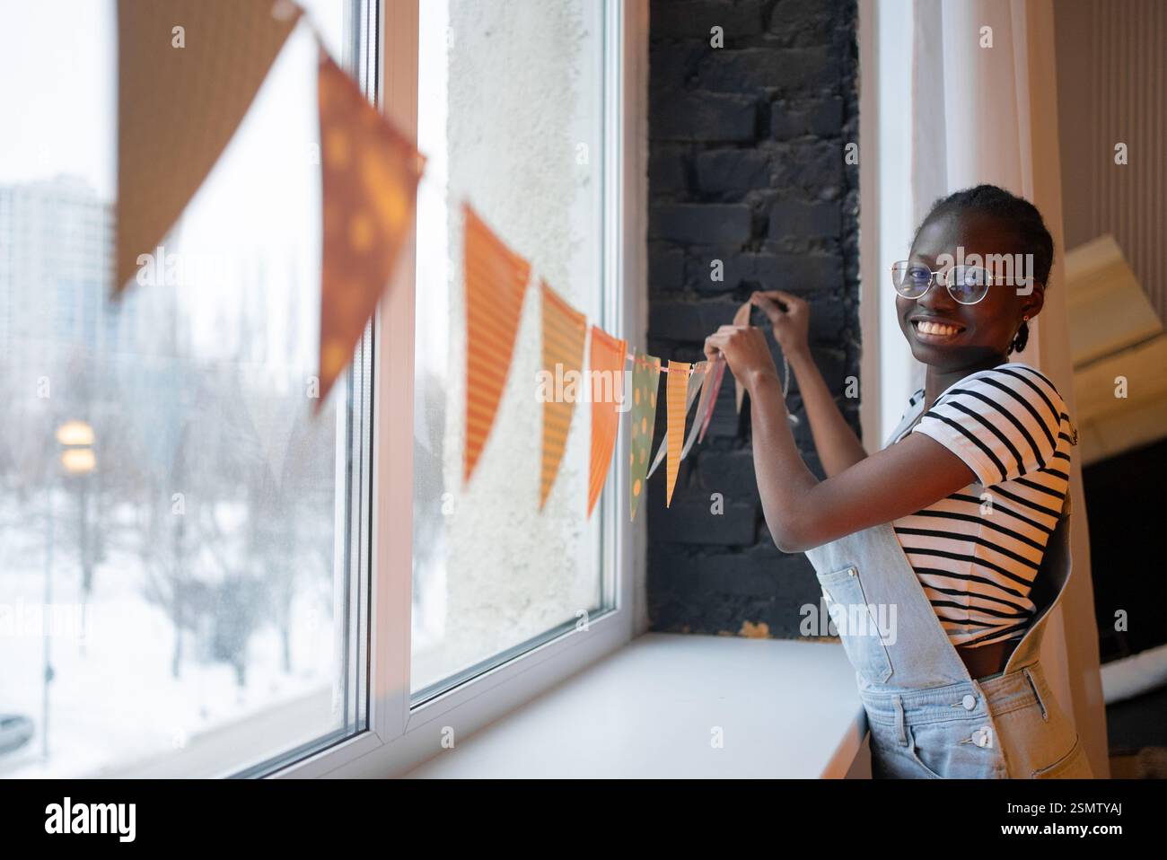 Smiling African American woman wearing denim overalls and eyeglasses ...