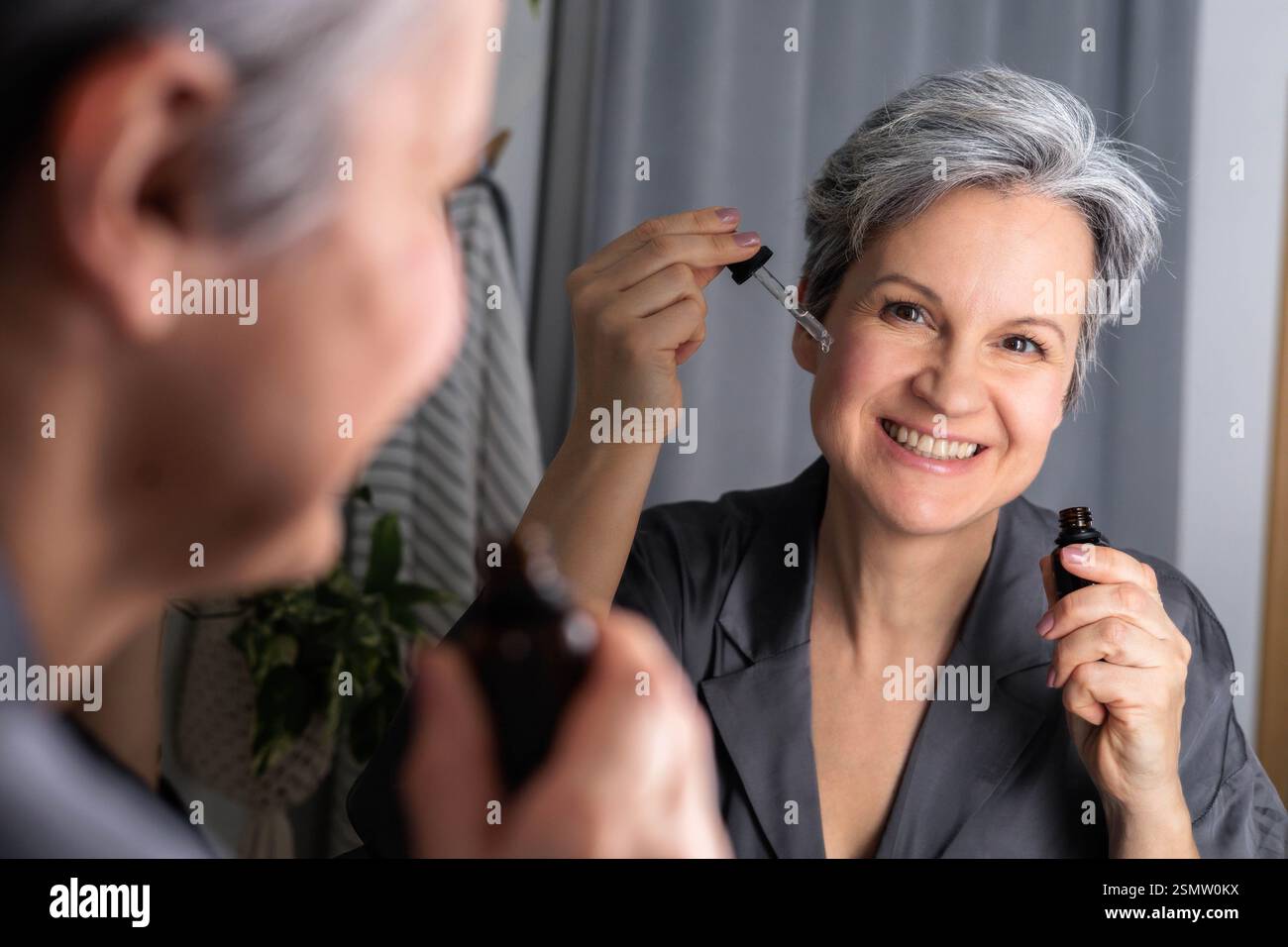 An adult beautiful woman of age during menopause with gray hair applies ...