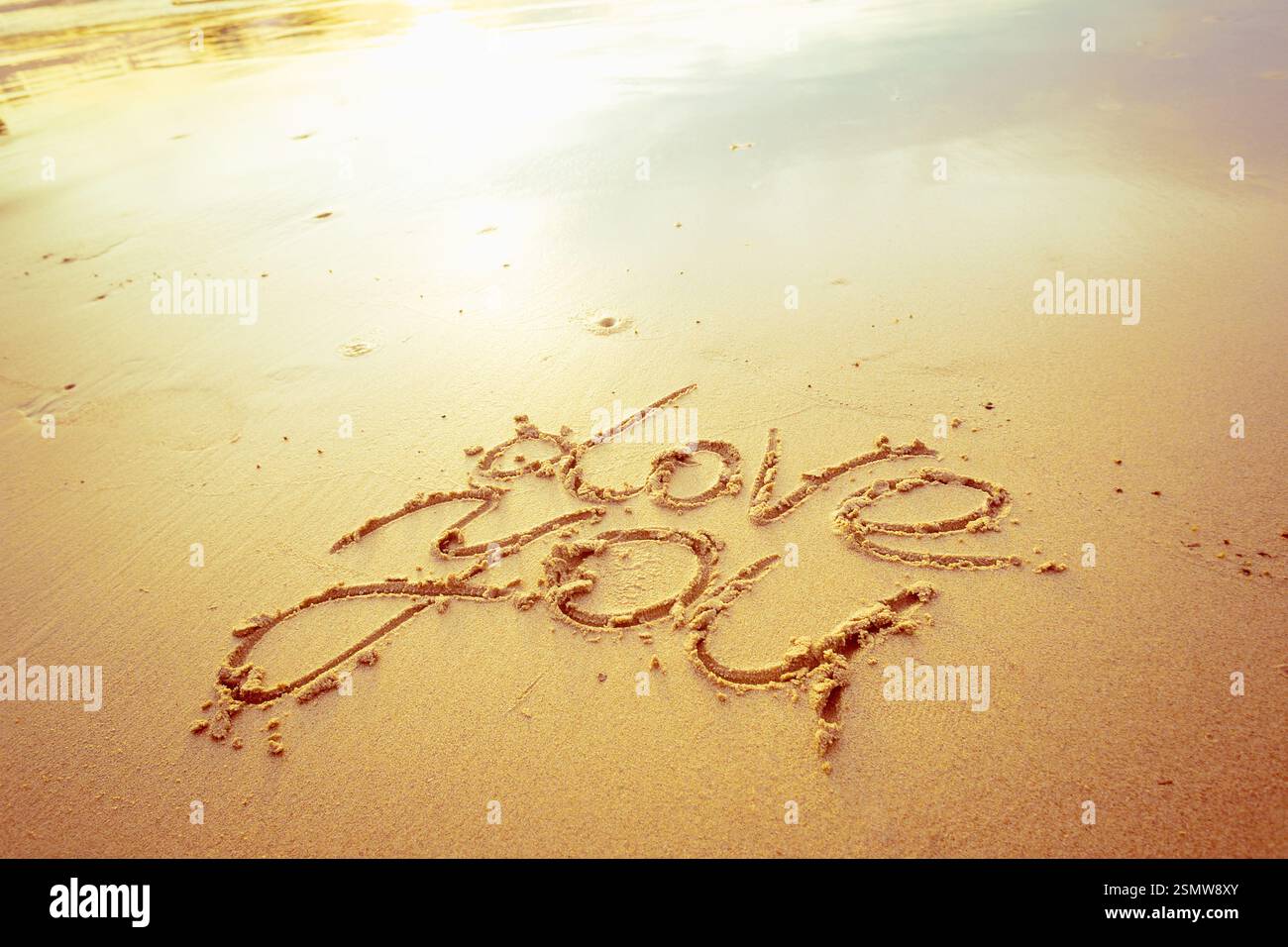 Writing love messages in sand on a beach during sunset creates a ...