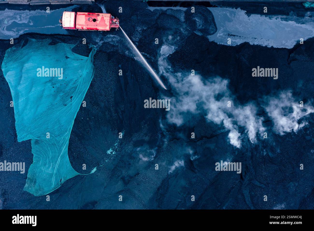 A firefighter extinguishes fire on coal heaps at a coal terminal on the ...