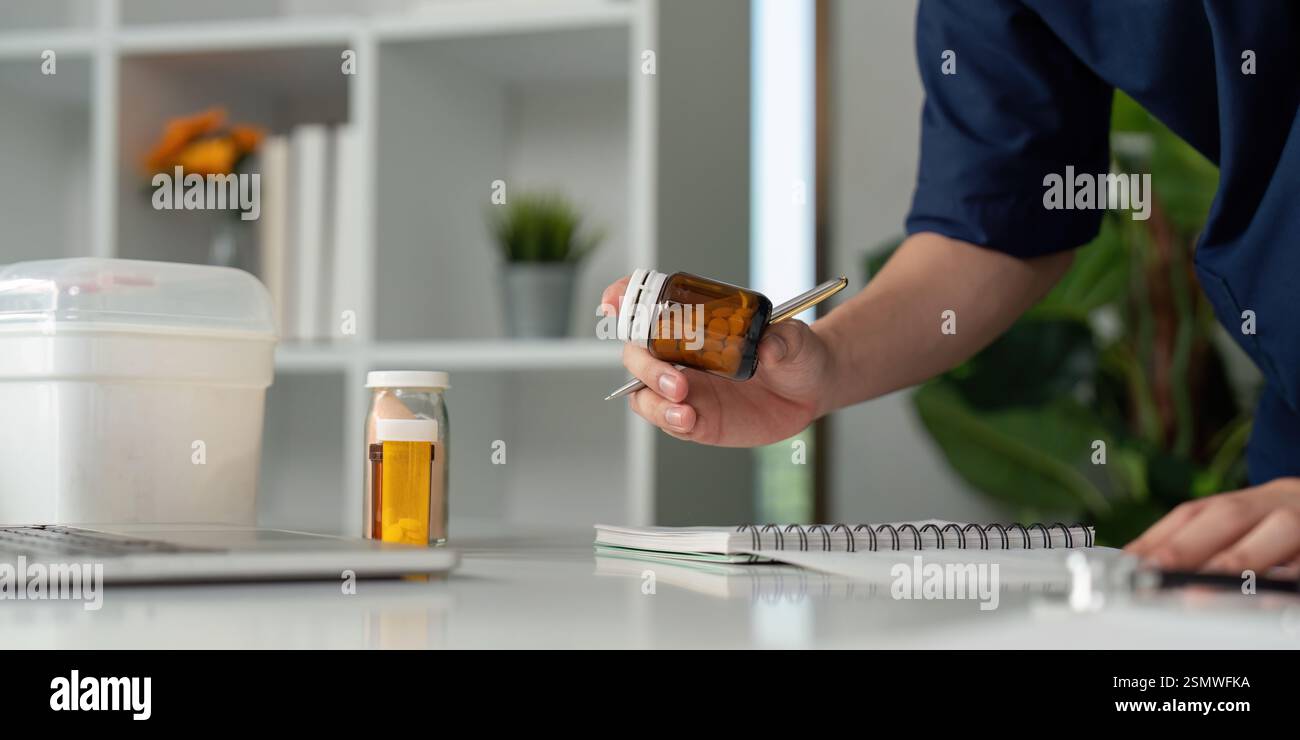 Medical student reviewing medication bottles and taking notes at a desk ...