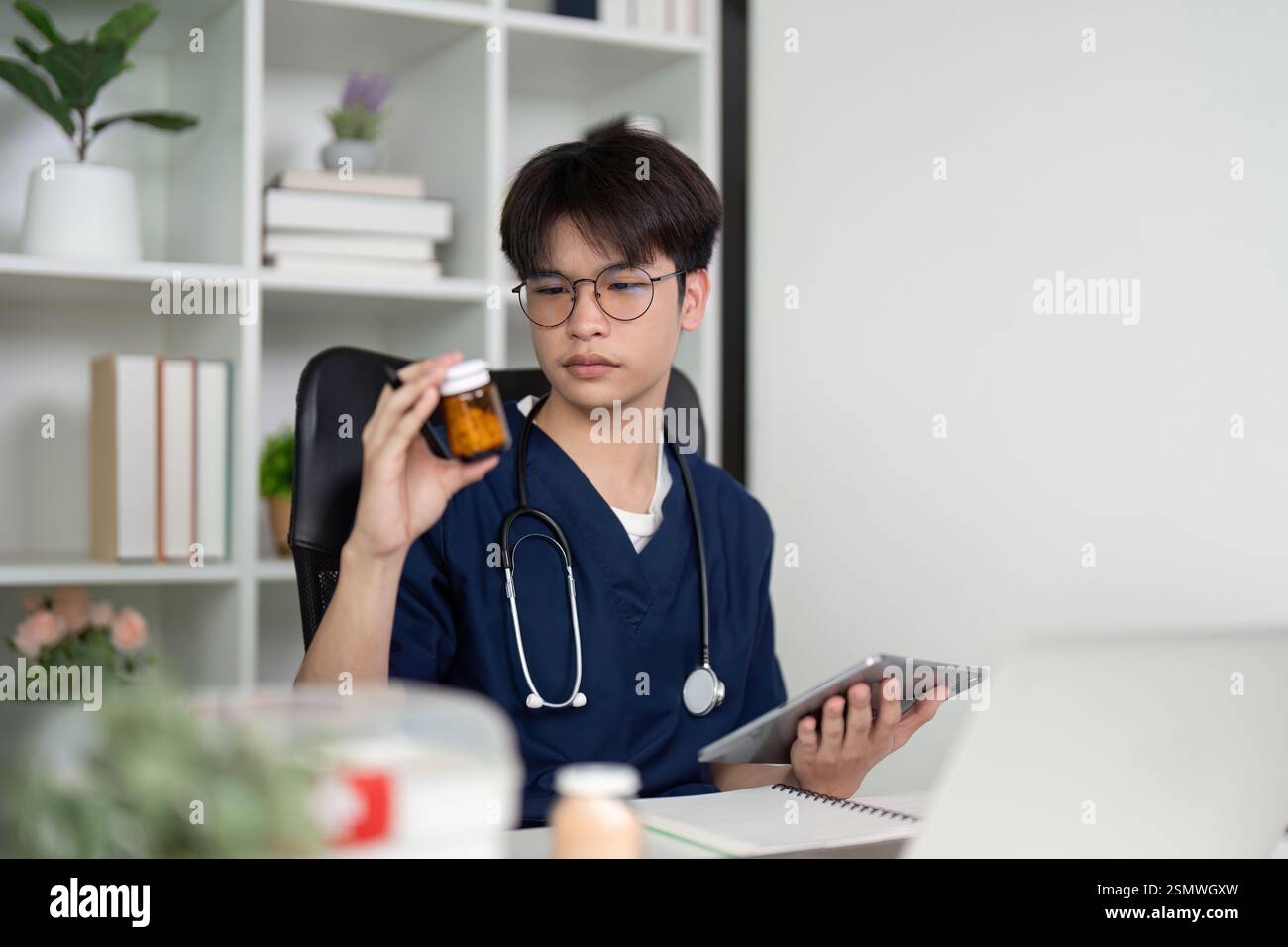 Medical student analyzing medication while using a tablet at a desk ...
