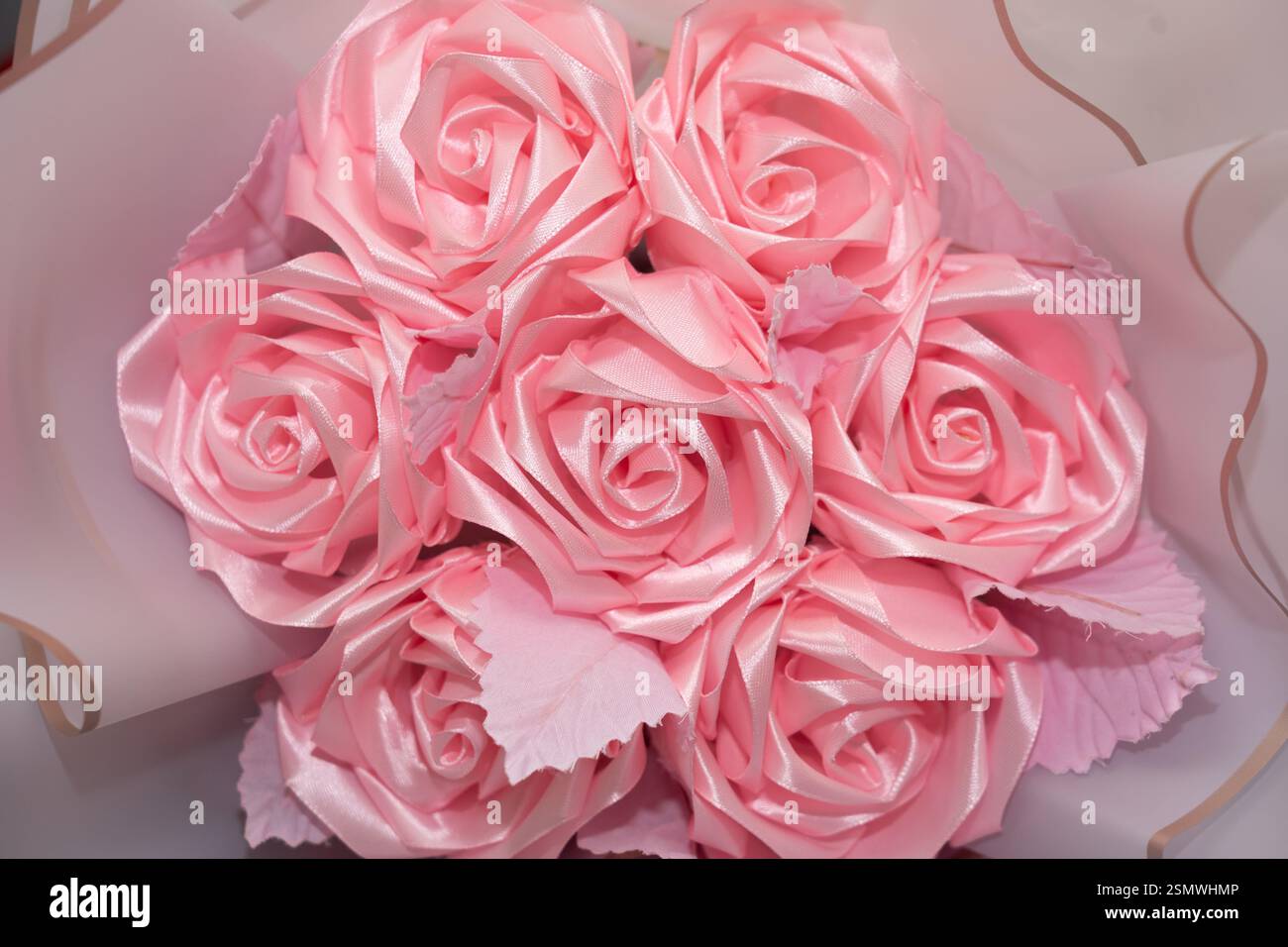A group of six pink ribbon roses crafted with care, surrounded by soft ...