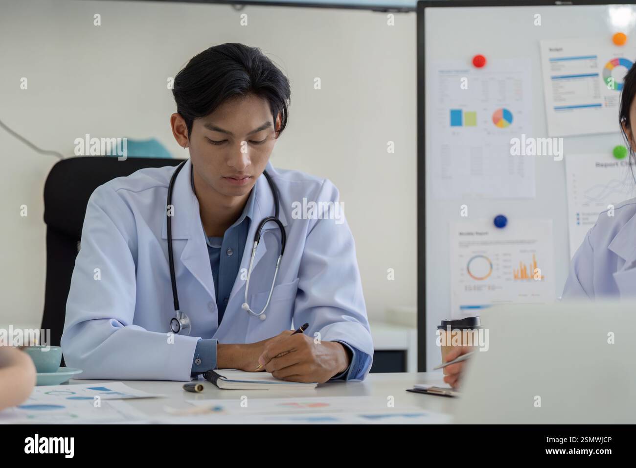 Doctor taking notes during a healthcare strategy meeting with ...