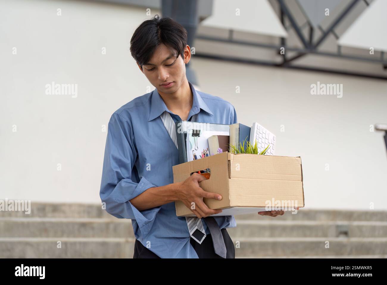 Professional man exiting workplace with a box of belongings, indicating ...