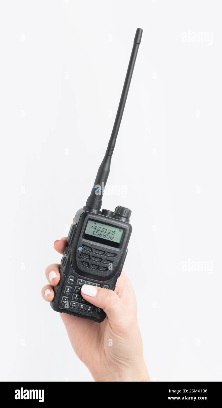 Handheld radio device held in a hand with a visible screen and antenna ...