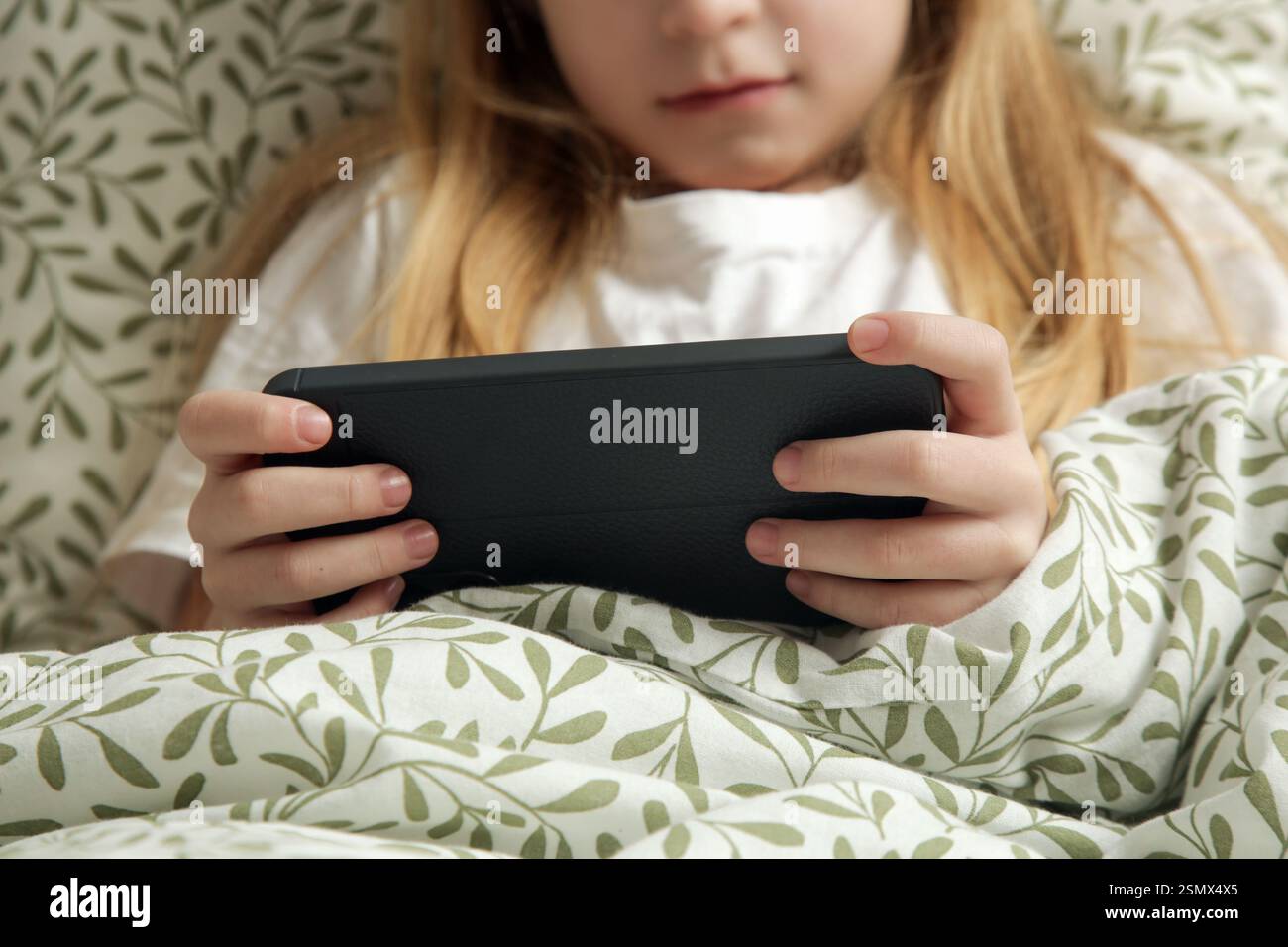 Cute little girl using smartphone at home, looking at screen before ...