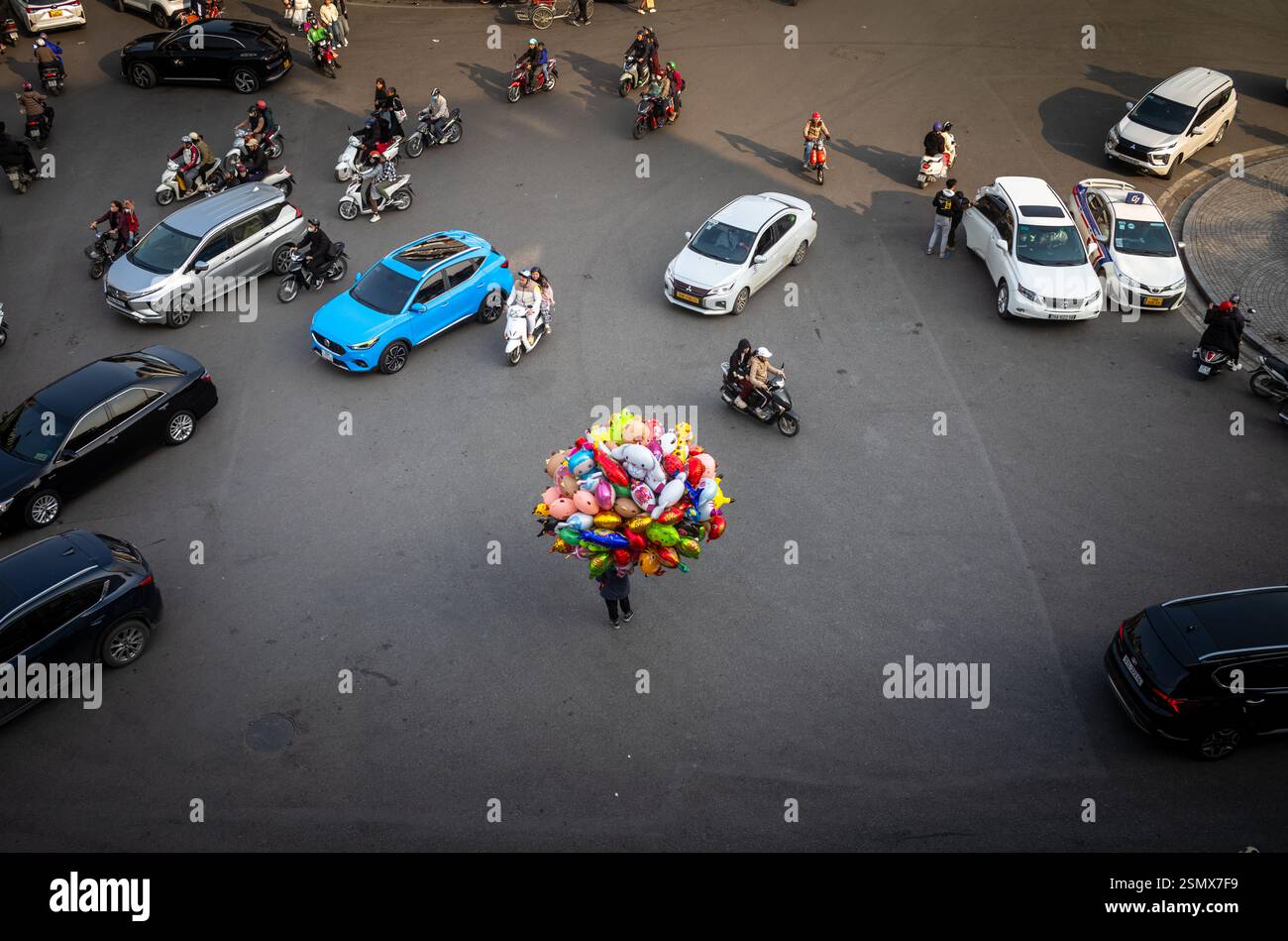 A seller of helium filled balloons shaped as animals stands in the road ...