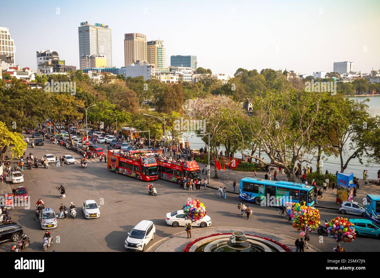 Looking down on open top tourist buses, cars, motorbikes and people at ...