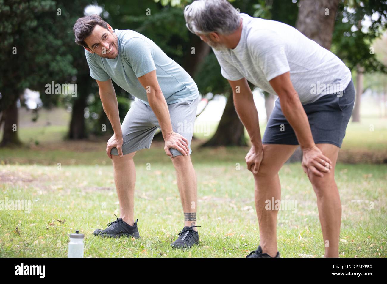 men resting leaning on their legs after exercising Stock Photo - Alamy